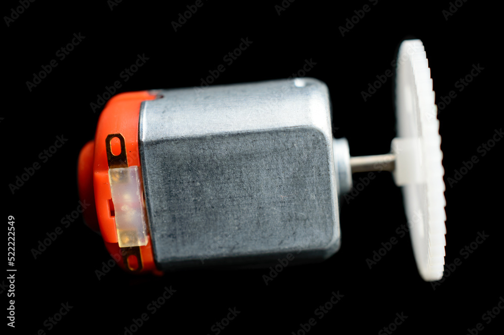 Direct current electric motor with white gear attached to it shaft on a ...