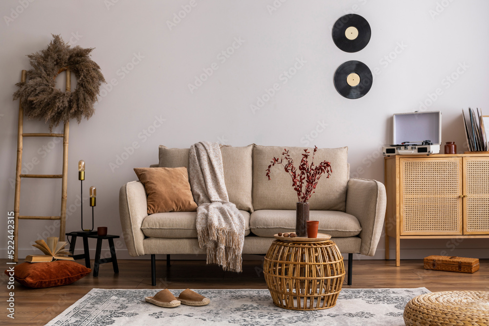 Interior design of harmonized living room with design beige sofa carpet pillow plaid coffee table vinyl recorder and elegant personal accessories. Beige wall. Minimalist home decor. Template. Stock Ad...
