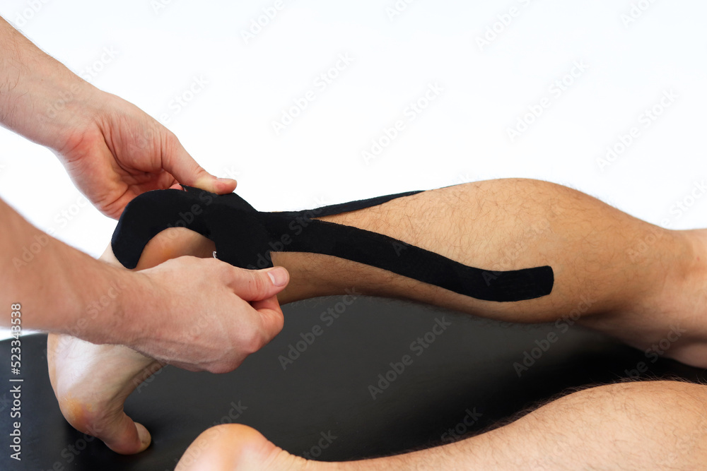 Kinesiology taping treatment with black tape on male patient injured ...