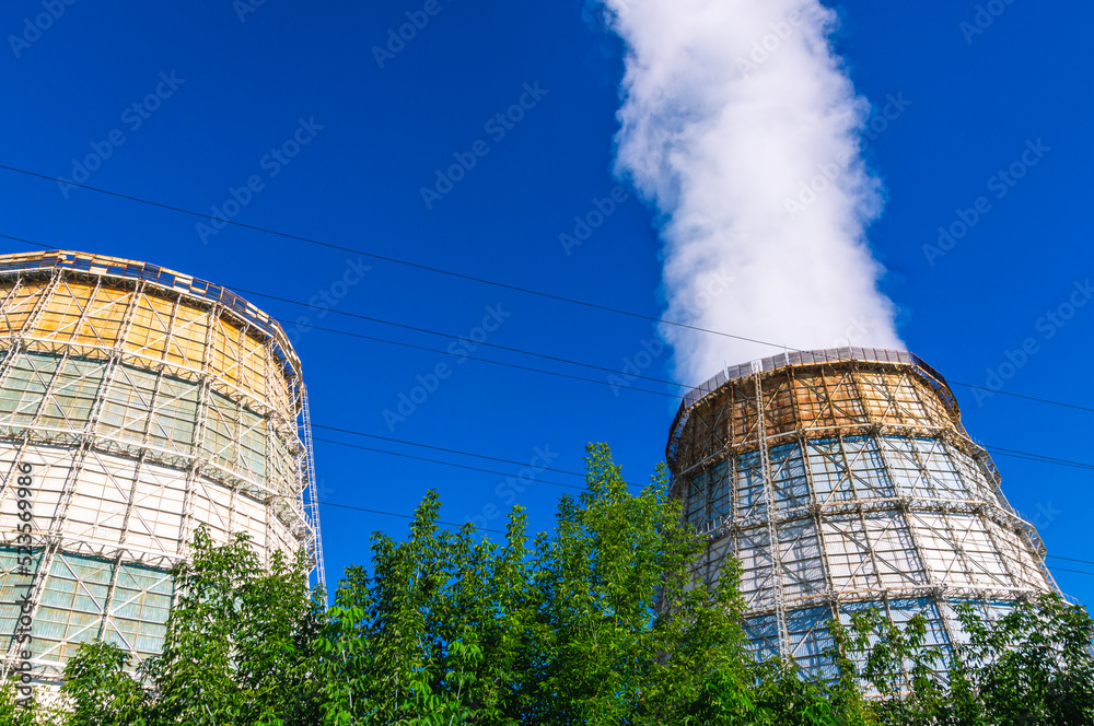 Large cooling towers of thermal power plants. White steam comes out of ...
