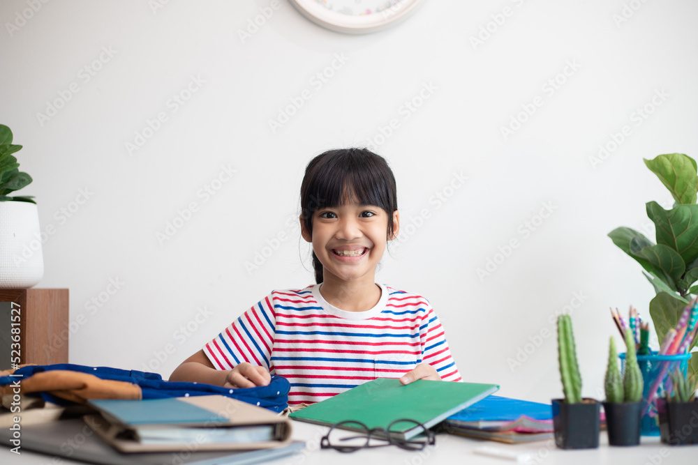 Asian cute primary school girls packing their school bags, preparing ...
