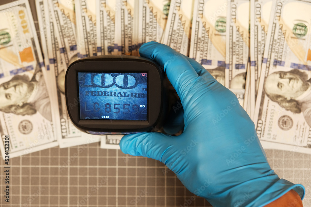 Checking the authenticity of dollars with a currency detector close-up ...