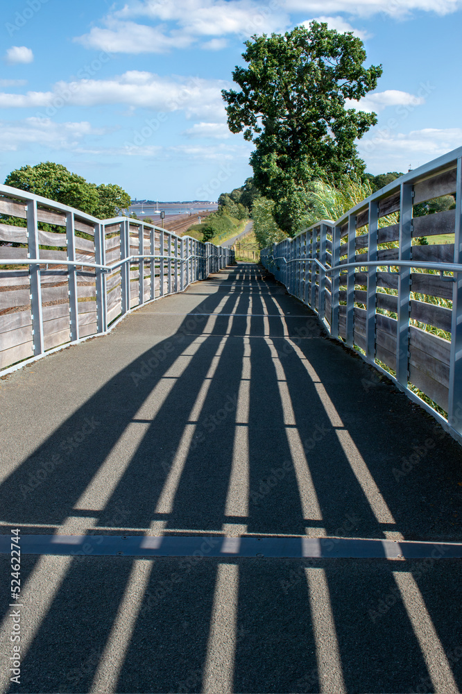 Public footbridge in stark shadowed sunlight. Long stripes of black ...