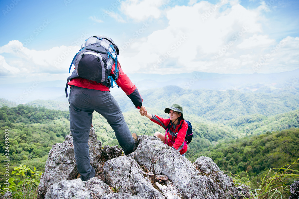 Stock-Foto „Person hike friends helping each other up a mountain. Man ...