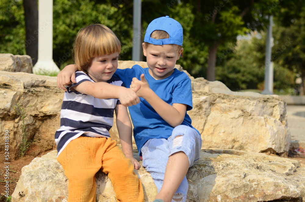 Two little boys, two friends, brothers are sitting on the street ...
