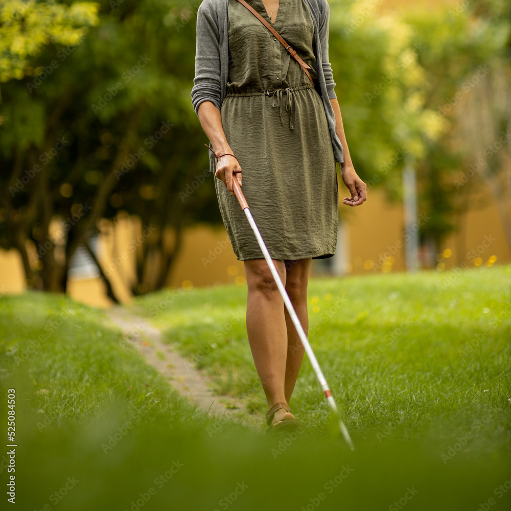 Blind woman walking on city streets, using her white cane to navigate ...