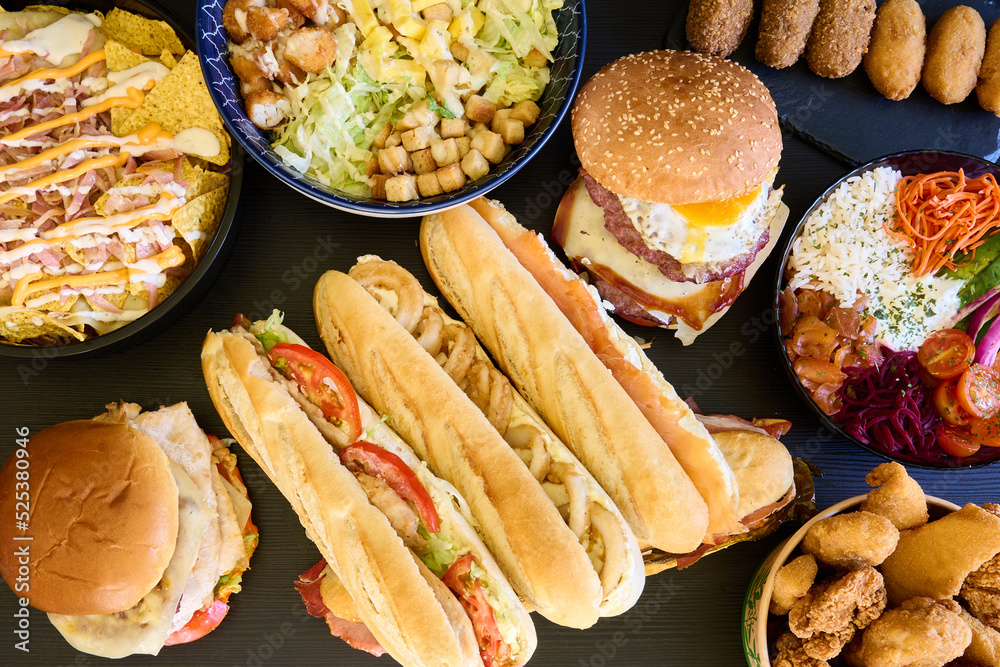 Table with various types of fast food. Sandwiches, burgers, chicken ...