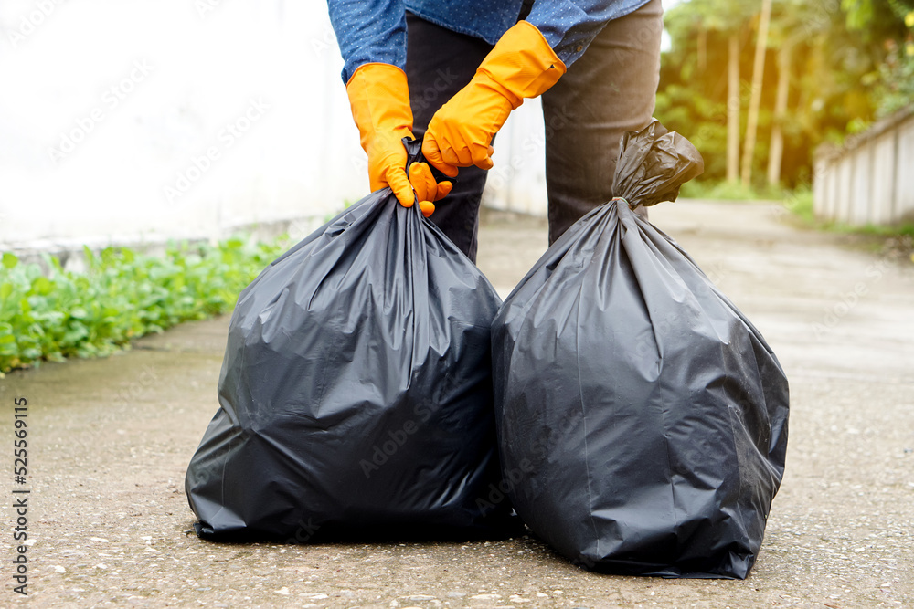 Foto Closeup man holds black plastic bag that contains garbage inside ...