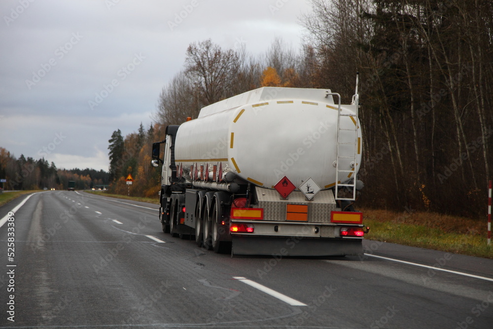 Oil tanker truck move on suburban highway road at autumn evening, rear ...