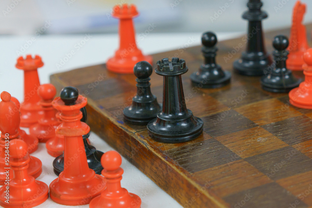 Side view of an old wooden chess board with red and black chess pieces ...