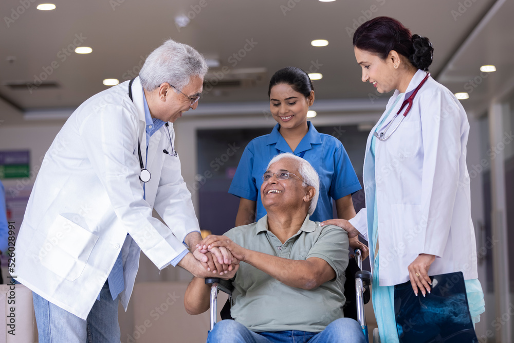 Doctors comforting disabled elderly patient in wheelchair at hospital ...