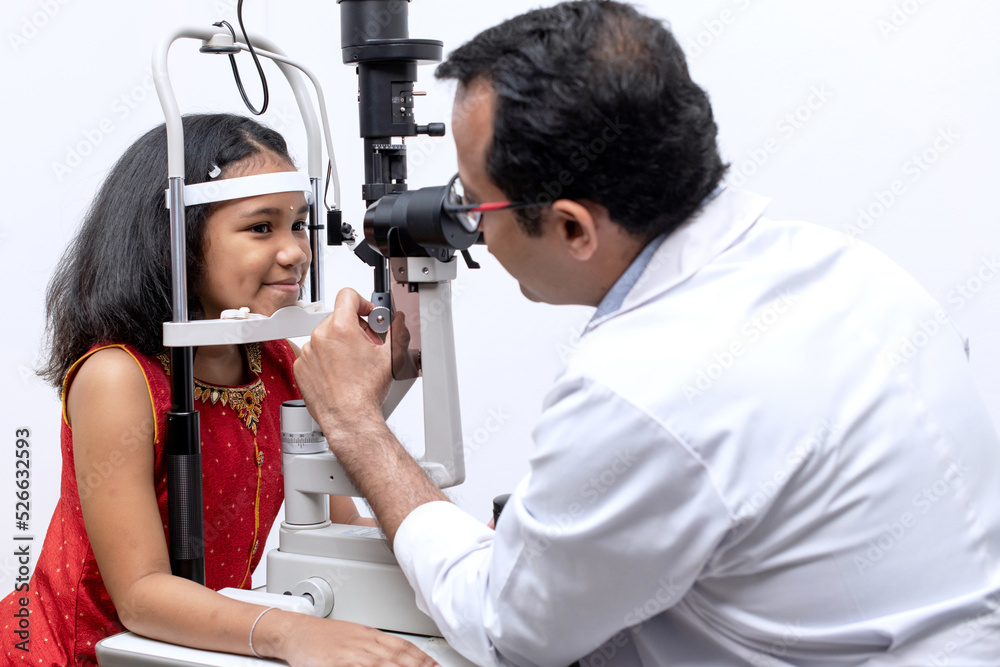 Indian girl and optometrist doing eye test with slit lamp in modern ...