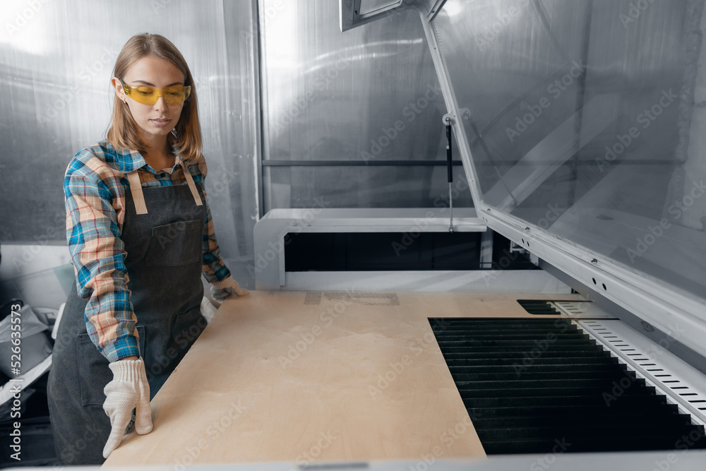 Industrial worker woman in uniform sets wooden sheet for laser CNC ...