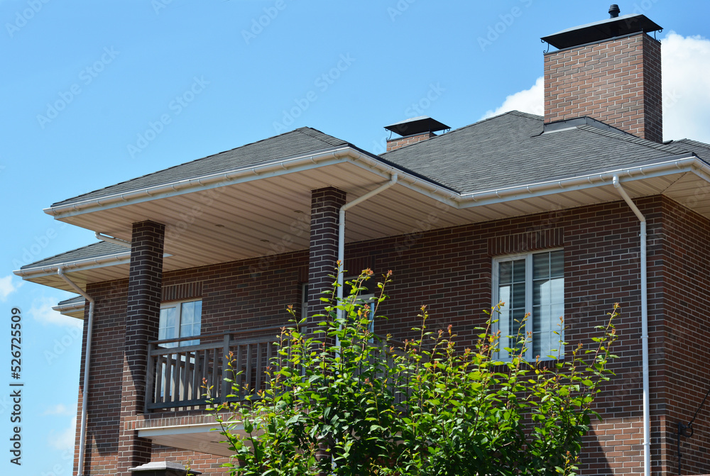 Brick house with asphalt shingles roof, chimney, balcony, rain gutter ...