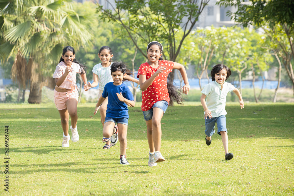 Group of happy playful Indian children running outdoors in summer park ...