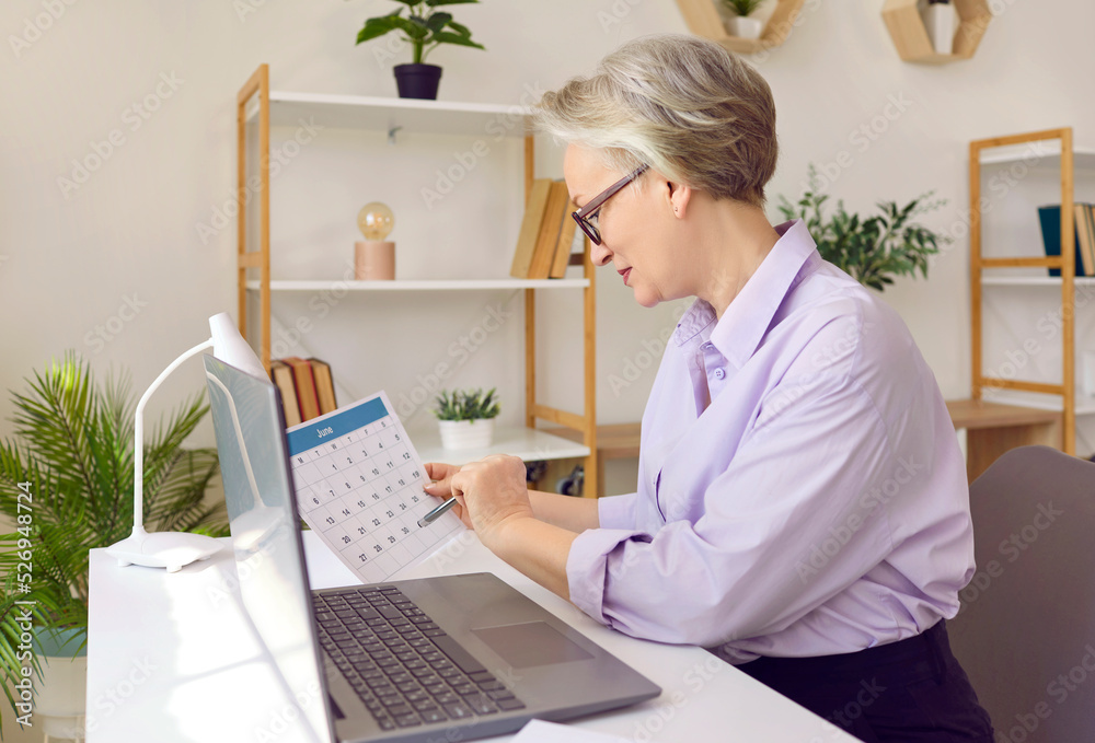Senior successful business woman planning her work week and checking ...