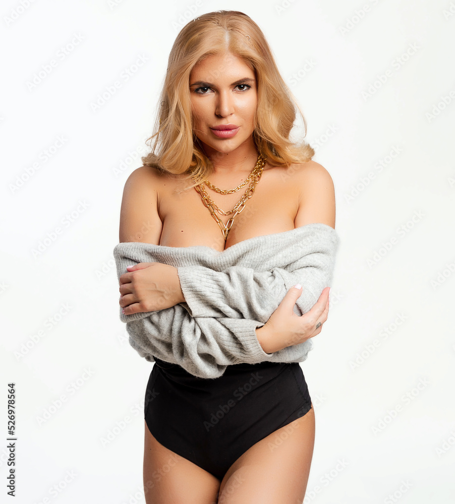 Gorgeous blonde woman is almost naked in knitted sweater stands with her naked legs. Sexy female ...