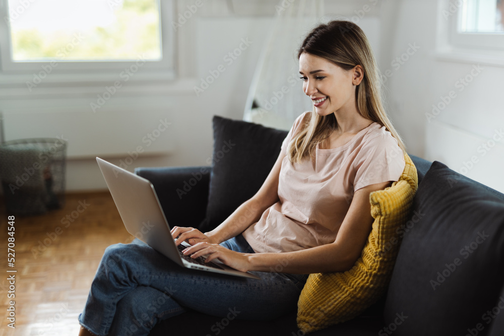 Stock-Foto „Happy young woman using computer on sofa at home“ | Adobe Stock