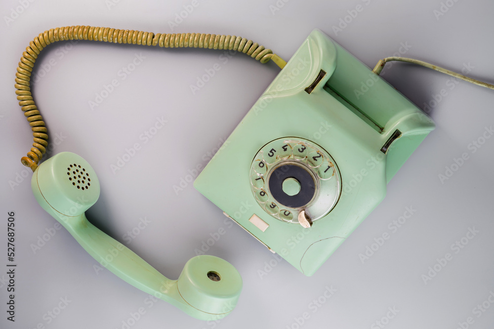 Old green antique rotary telephone with removed receiver on blue ...