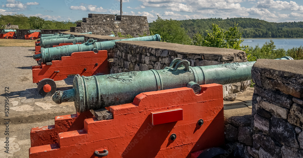 Row of 18th century bronze cannons with red base in firing position ...