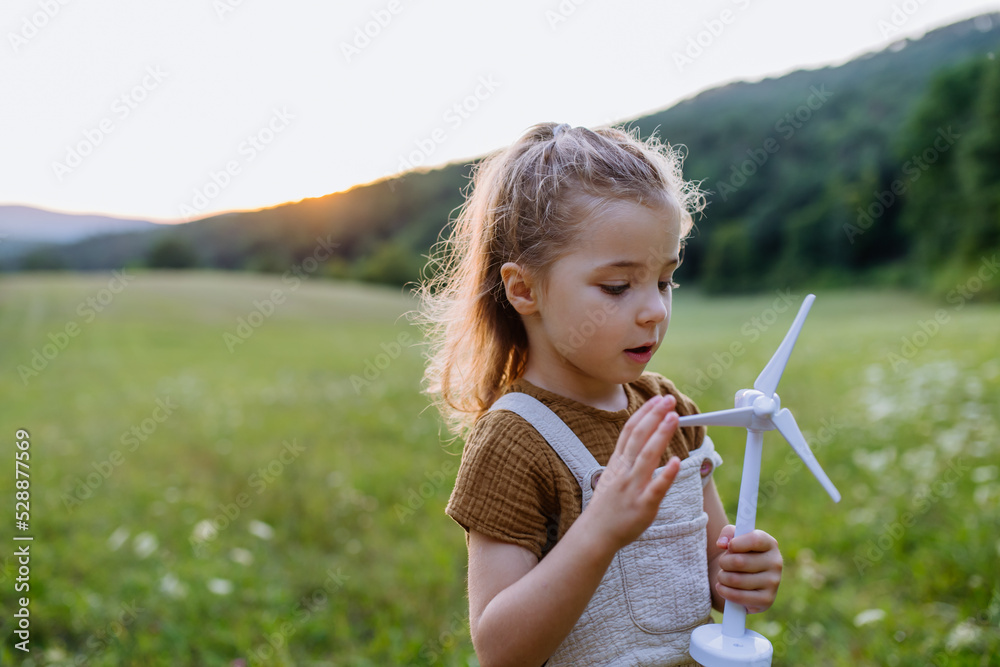 Little girl standing in nature with model of wind turbine. Concept of ...