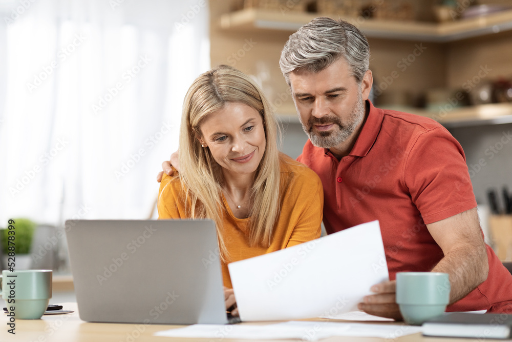 Cheerful middle aged couple paying bills, reading papers Stock Photo ...