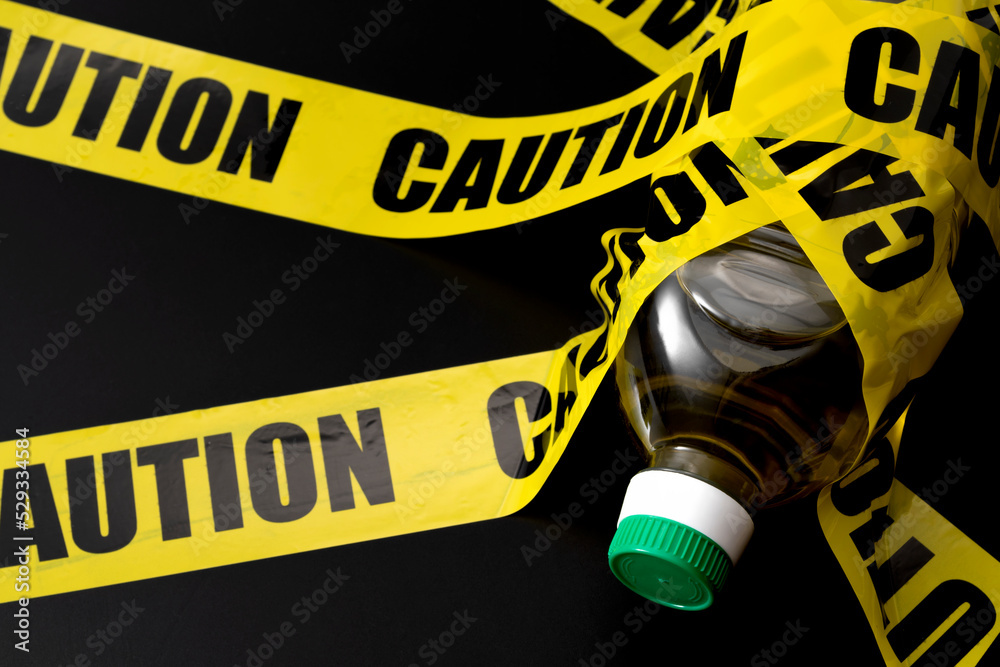 Bottle of vegetable oil (seed oils) wrapped in caution tape concept for ...