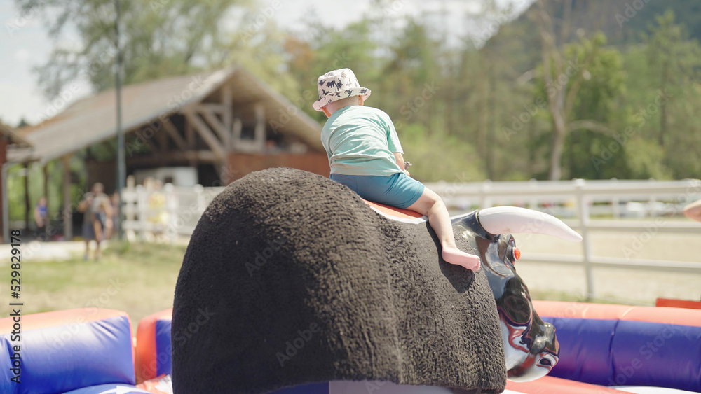 Kid on mechanical bull rodeo riding at western festival Stock Photo ...