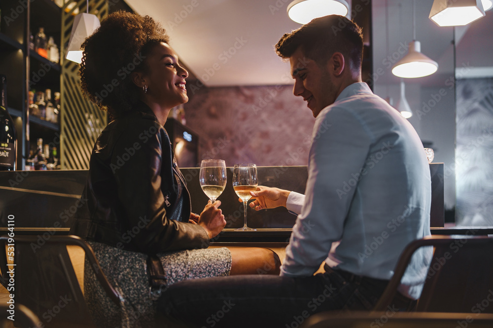 Romantic couple on a date talking holding a glass of white wine sitting ...
