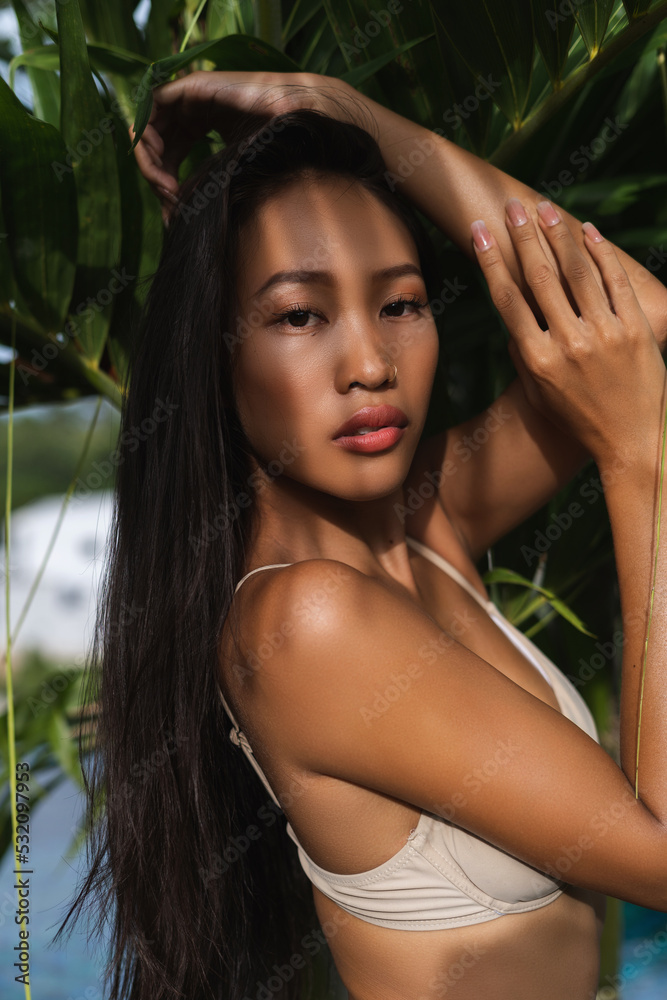 Beautiful asian thai woman with soft smooth clean dark tanned skin posing by palm leaves Stock ...
