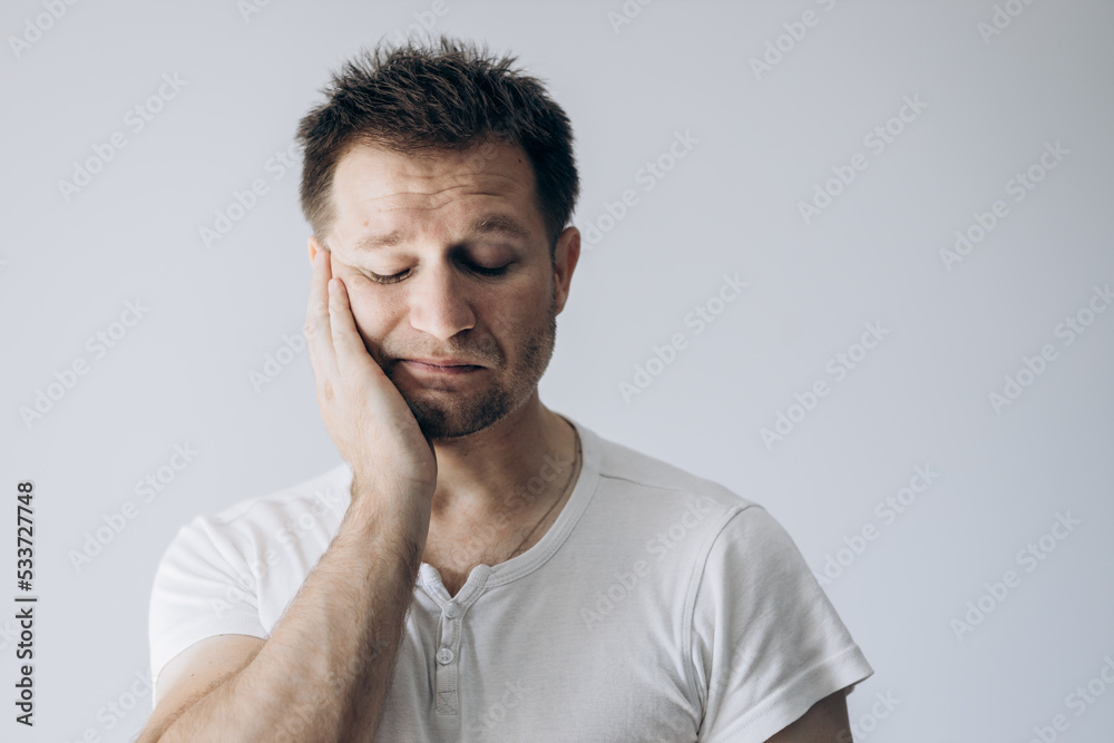 Stress at work. Toothache in man. Guy holds his hand to his face from ...