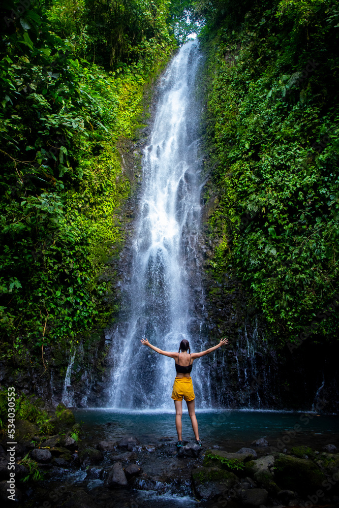 Foto brave girl stands in front of a mighty waterfall with her hands ...