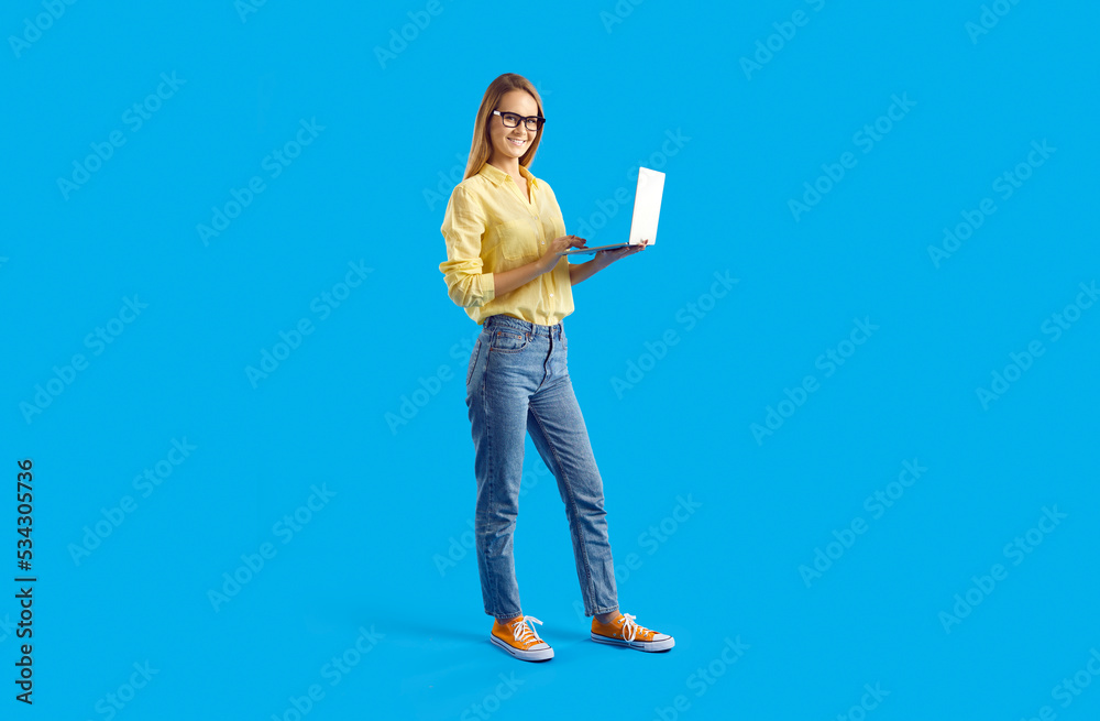 Happy young woman using modern laptop computer. Full body studio shot ...