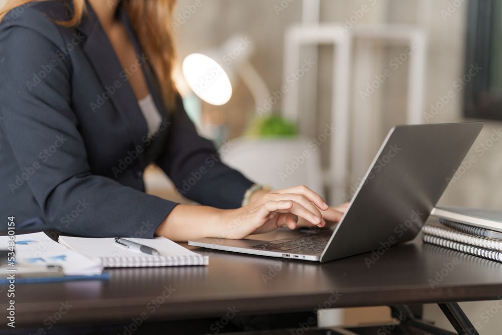 Using laptop, Young pretty asian stock manager checking list of product ...