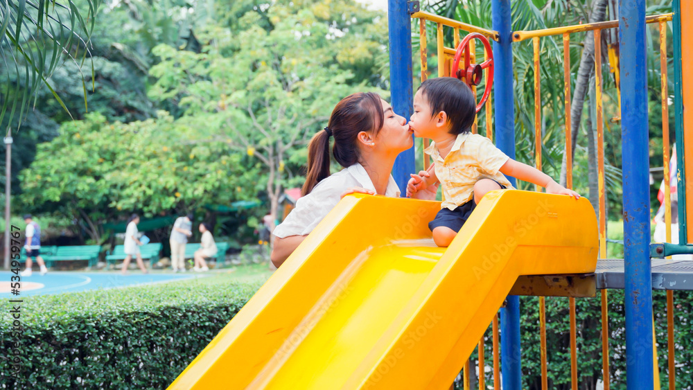 Mother encourage the little boy her by kissing before the little son ...