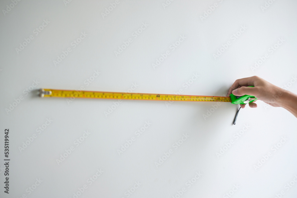 Man hand using tape measure for measuring with wall backgrounds at home ...