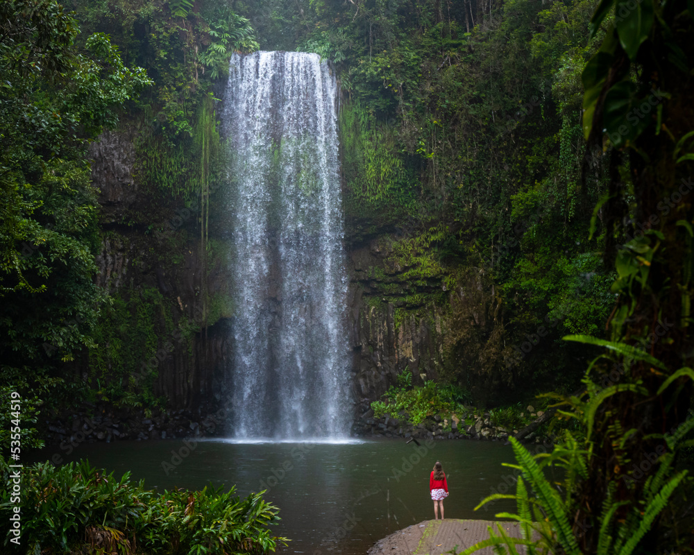 A girl in a red sweatshirt and red and white skirt stands over a ...