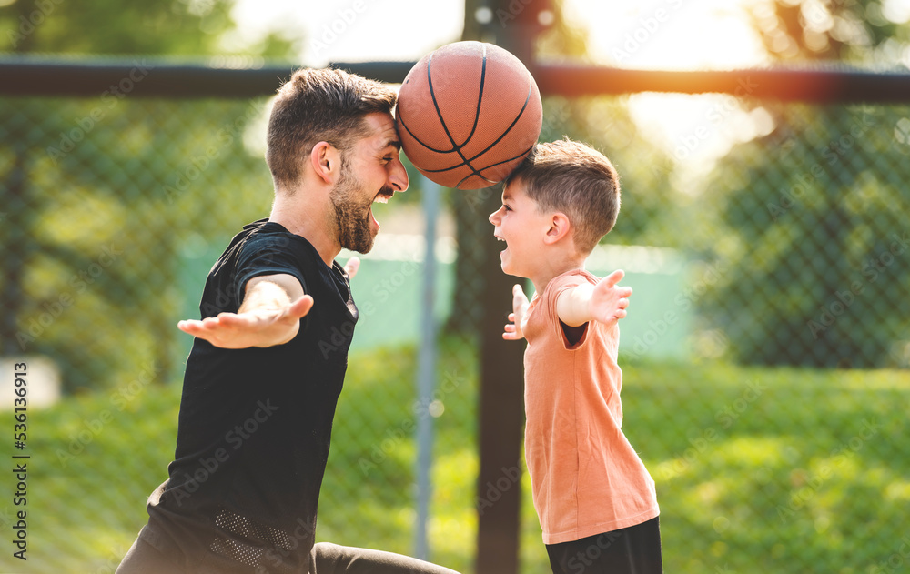 man and young boy playing basketball on a court, teaching little player ...