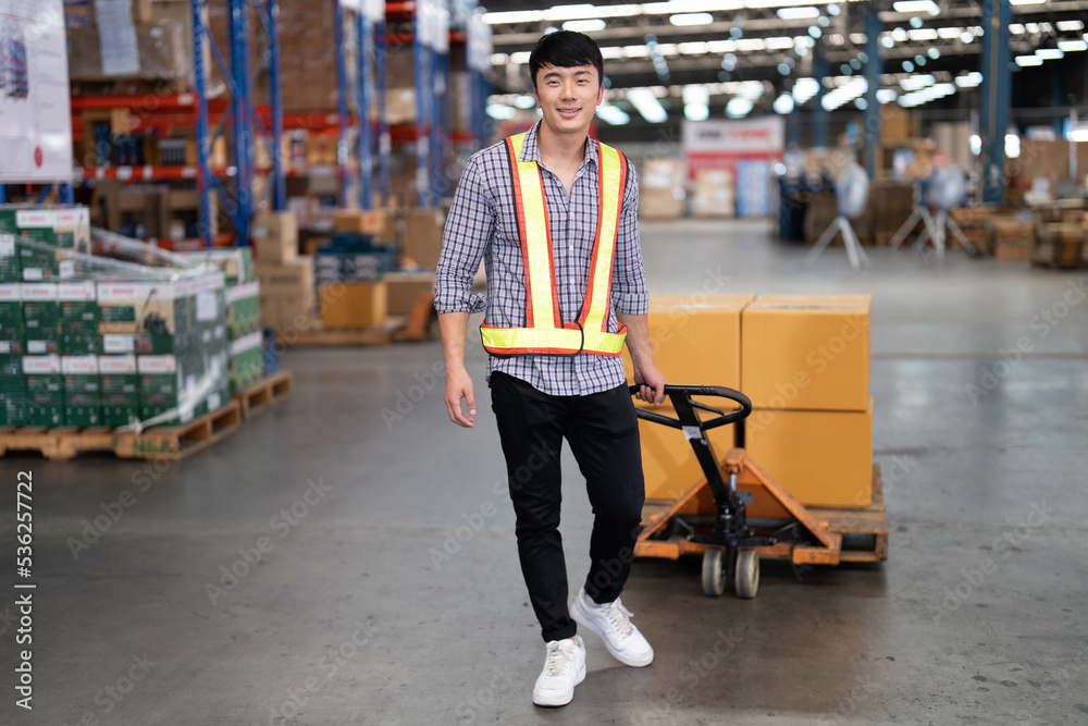 Warehouse worker pulling manual hand pallet lift carry stacked boxes to ...