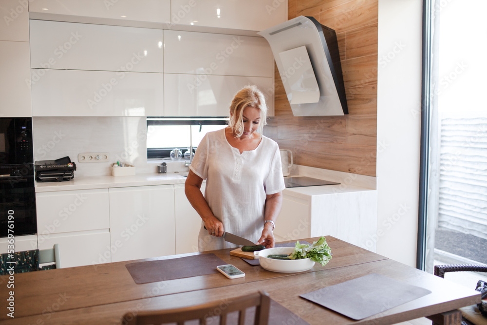 Middle- aged woman cooking in the kitchen at home. 60s year old woman ...