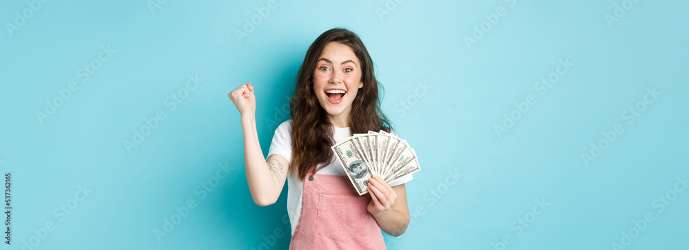 Excited smiling girl fist pump and hold money prize, winning cash ...