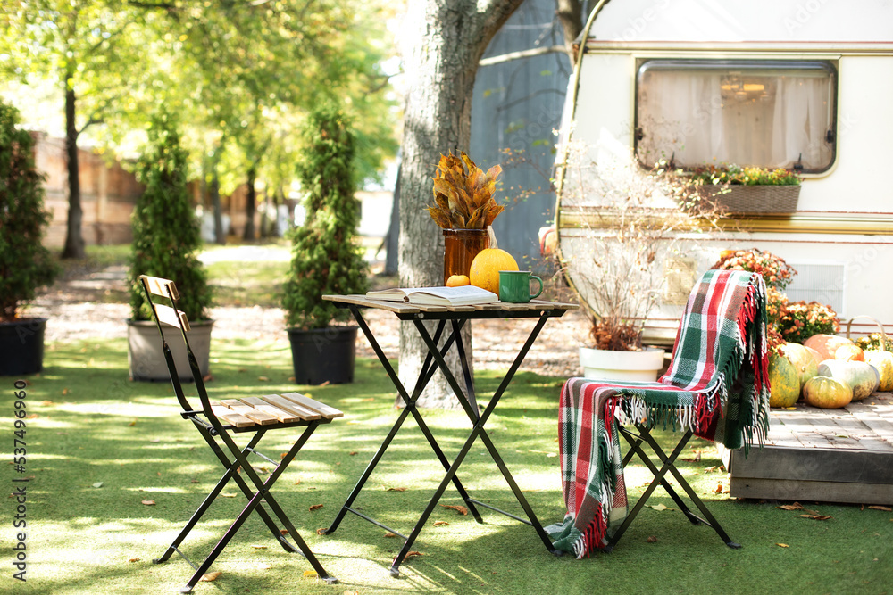 Interior cozy campsite with flowers and pumpkins. Wooden RV house porch ...