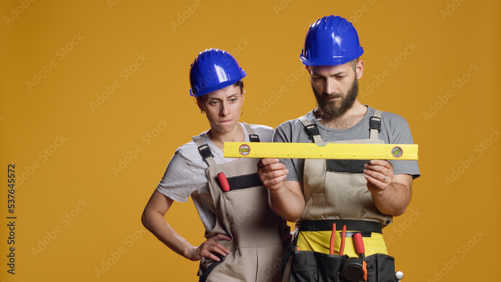 Construction workers using water level tools to measure flat surface ...
