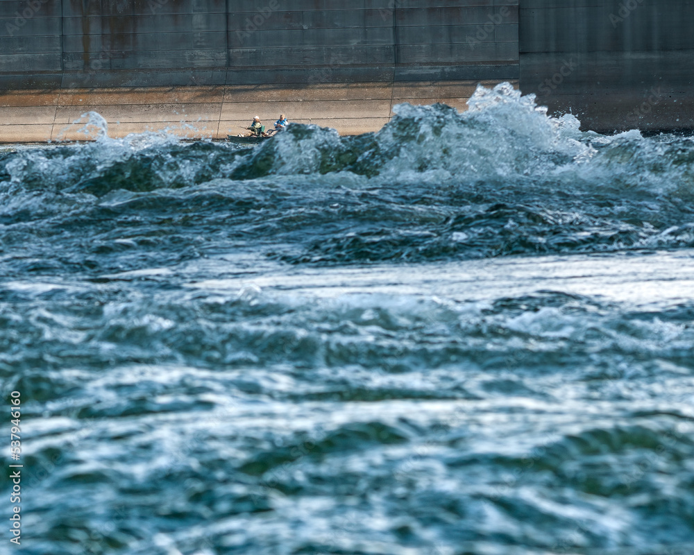 Stock-Foto „Two men fishing from a boat in dangerous water, below a dam ...