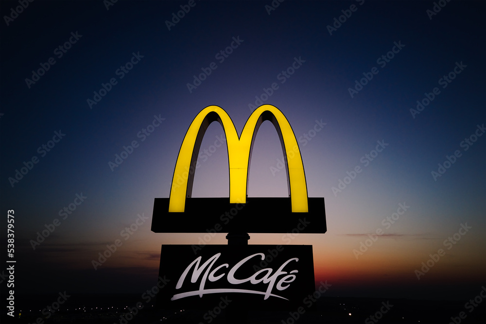 Glowing McDonalds restaurant sign against night sky. Logo of McCafe ...