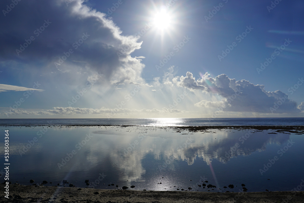 perfect mirror reflection of the stormy clouds and sun in the ocean by ...
