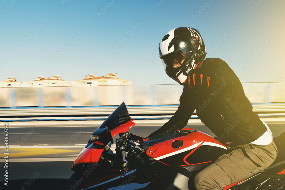 Side view of a motorcycle rider riding red race motorcycle on the ...