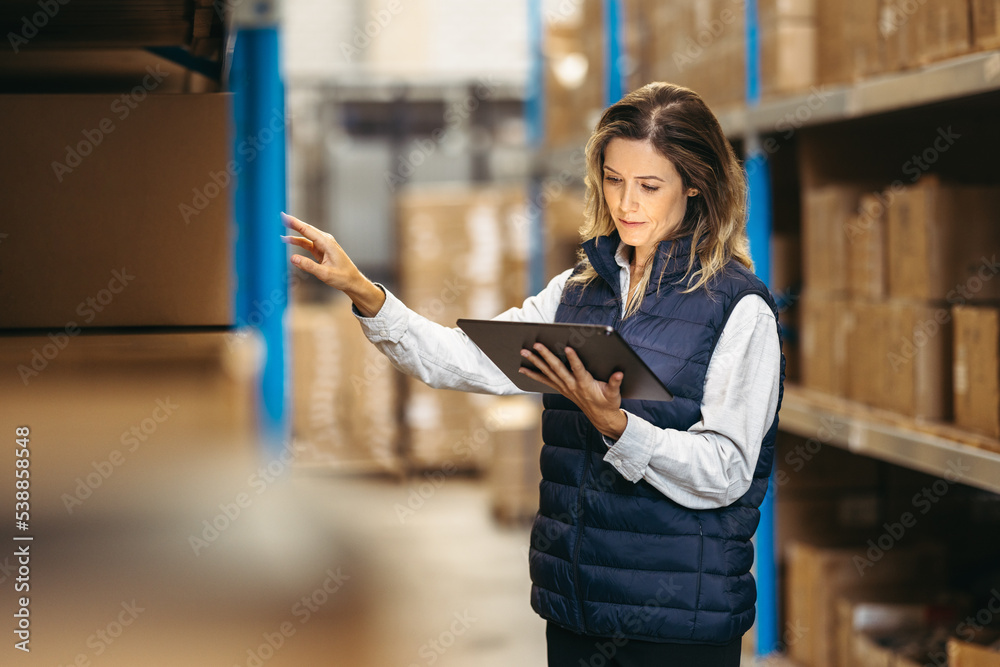 Female manager using a digital tablet while doing a stock take in a ...