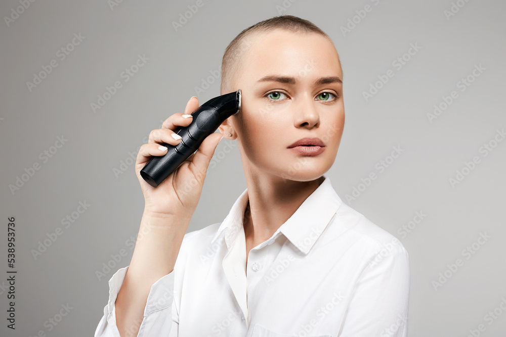 beautiful young woman cutting her hair. bald Girl with hairclipper ...