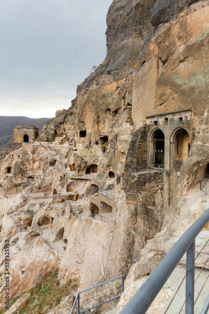 Complex of Vardzia cave monastery structures carved on mountain slope with view of temple of ...